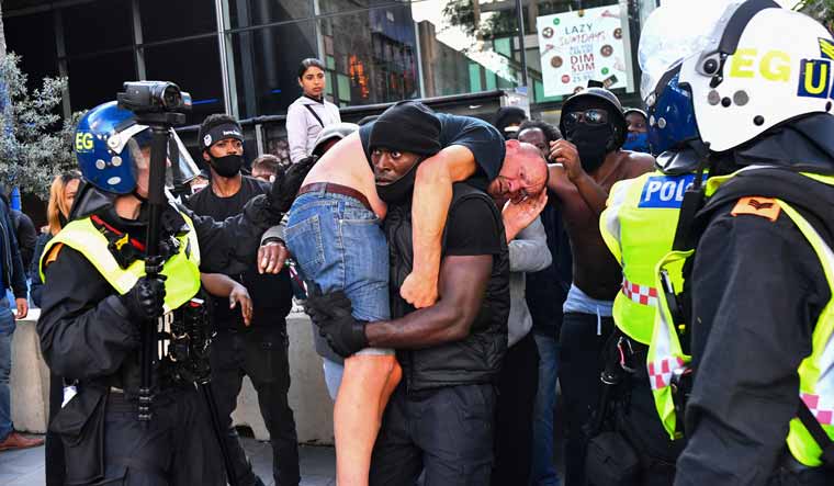 Image of black protester carrying injured white man in London goes ...